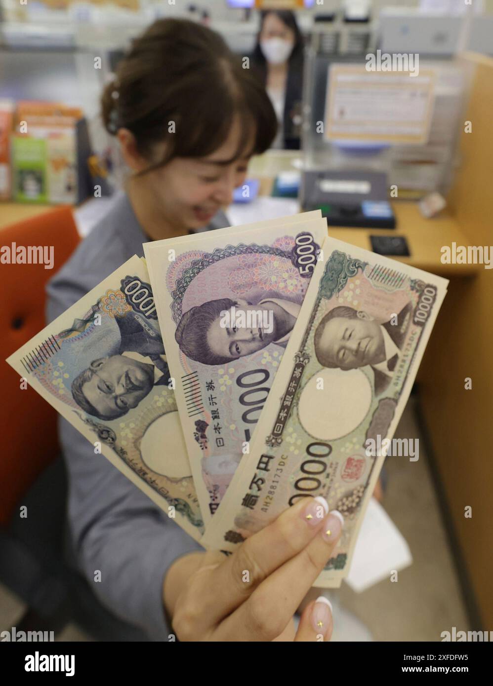 A woman shows three types of new banknotes which were issued for the ...