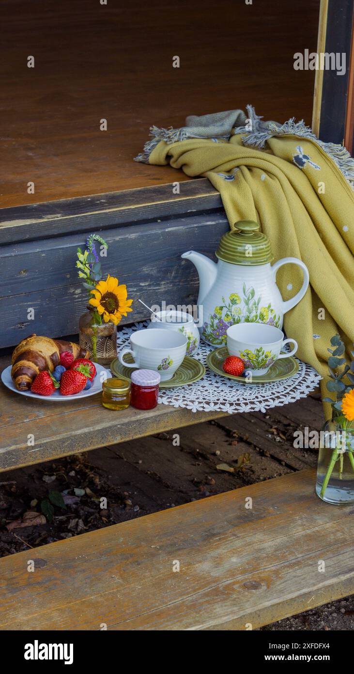 Morning summer tea with flowers and fruits on the veranda in the ...