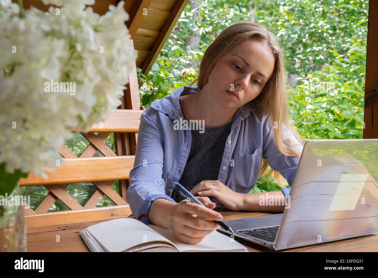 Female student has online lesson education outdoor in garden wooden ...