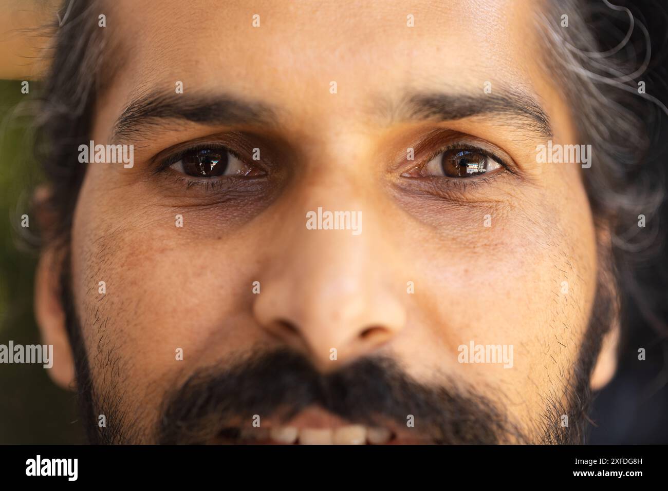 Close-up of Indian male face with beard and mustache, looking directly ...