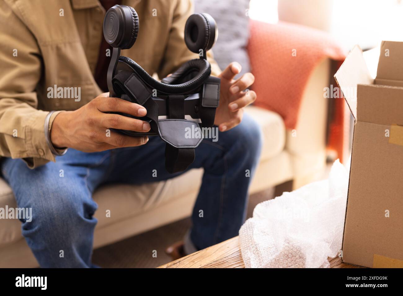 Unboxing and examining new VR headset, man sitting on couch in living ...