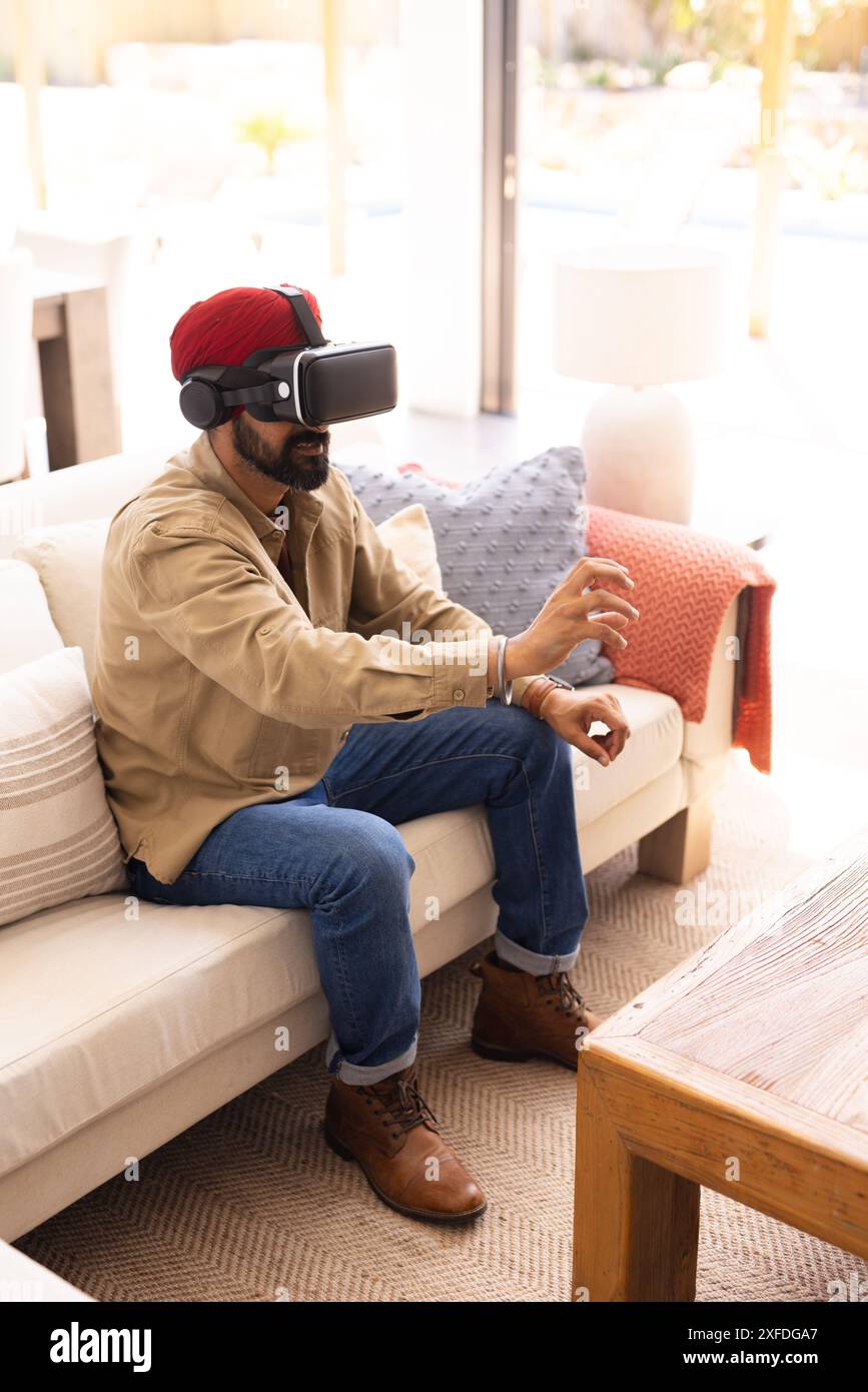 Using VR headset, man sitting on sofa and interacting with virtual ...