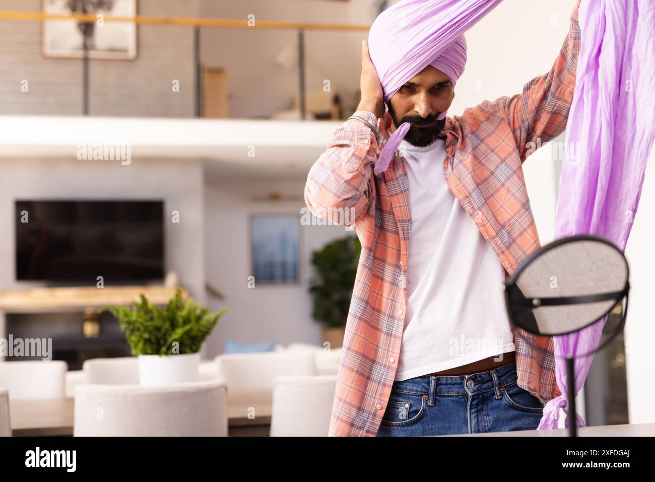 Man adjusting turban in front of mirror at home, focusing on appearance ...