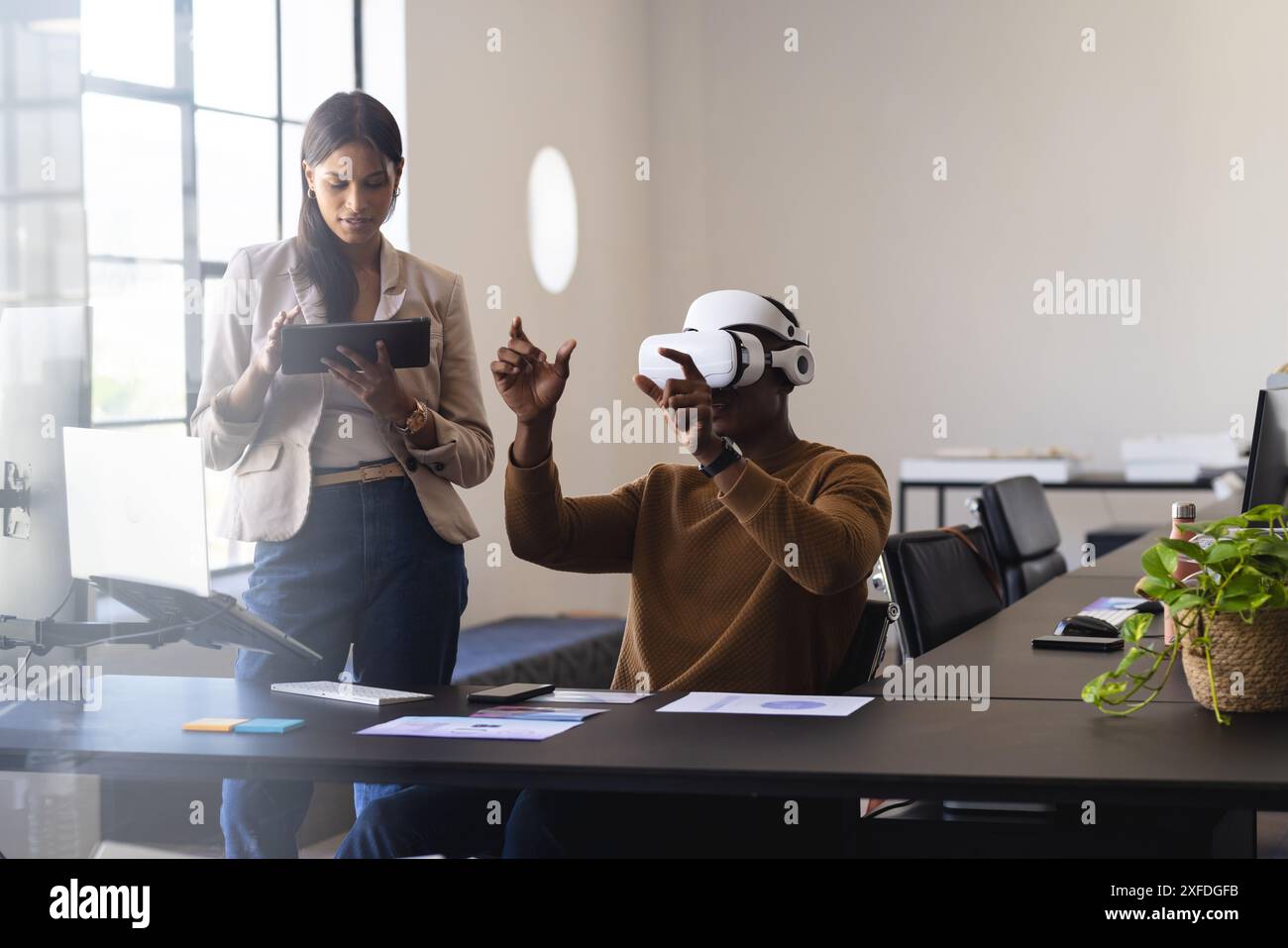 Using VR headset, man interacting with virtual environment while woman ...