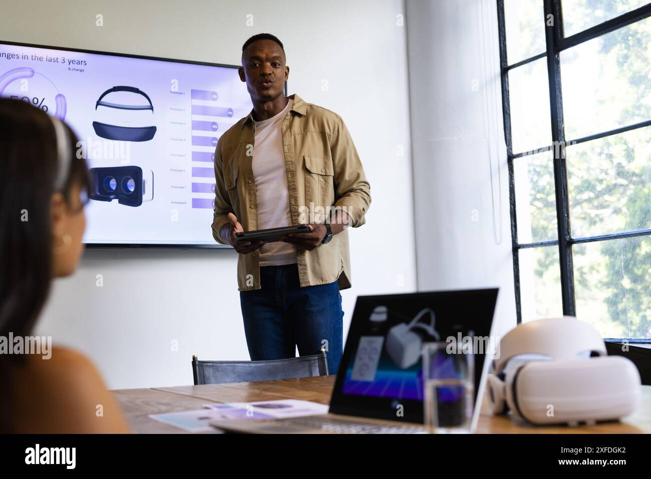 Presenting data, man holding tablet and explaining VR headset ...