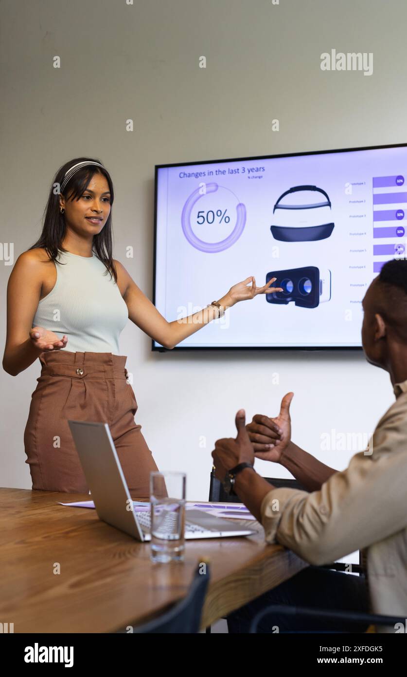 Presenting data on screen, woman discussing virtual reality trends with ...