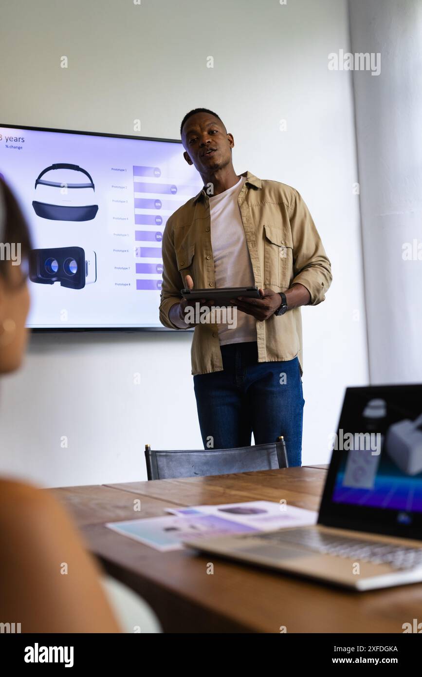 Presenting data, man holding tablet and explaining VR headset ...