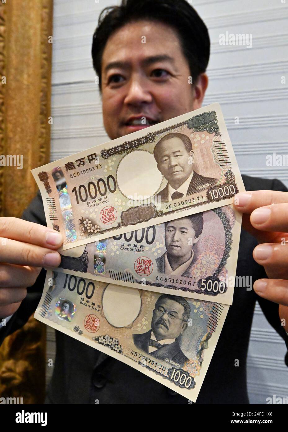 A man shows three types of new banknotes which were issued for the ...