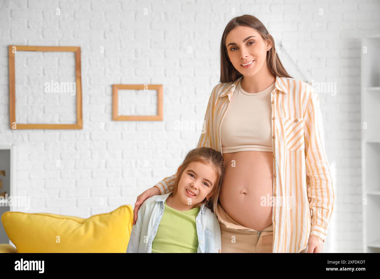 Cute little girl with her pregnant mother hugging at home Stock Photo ...