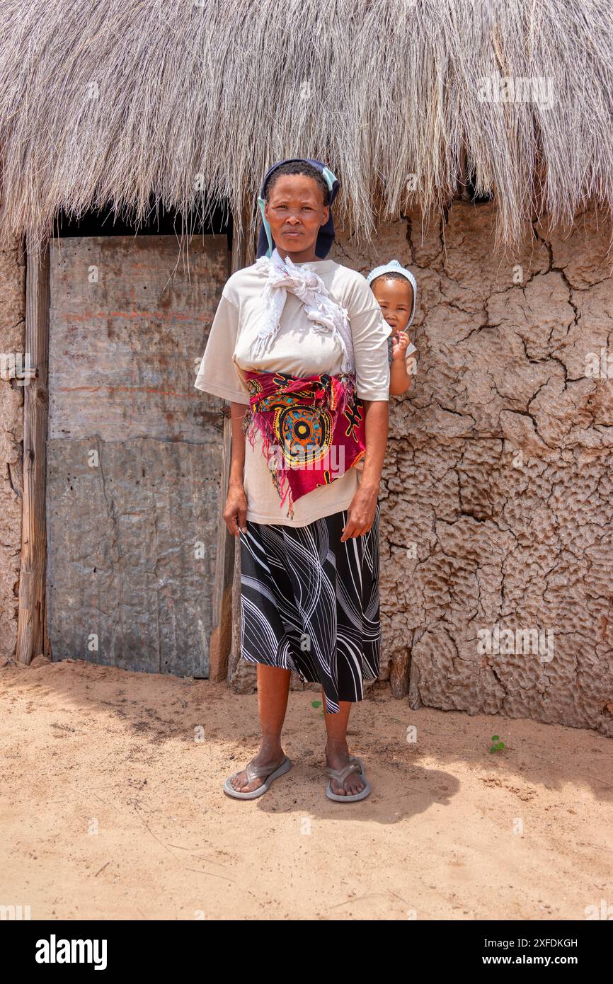 village african woman piggyback carry child in the back, mud house in ...