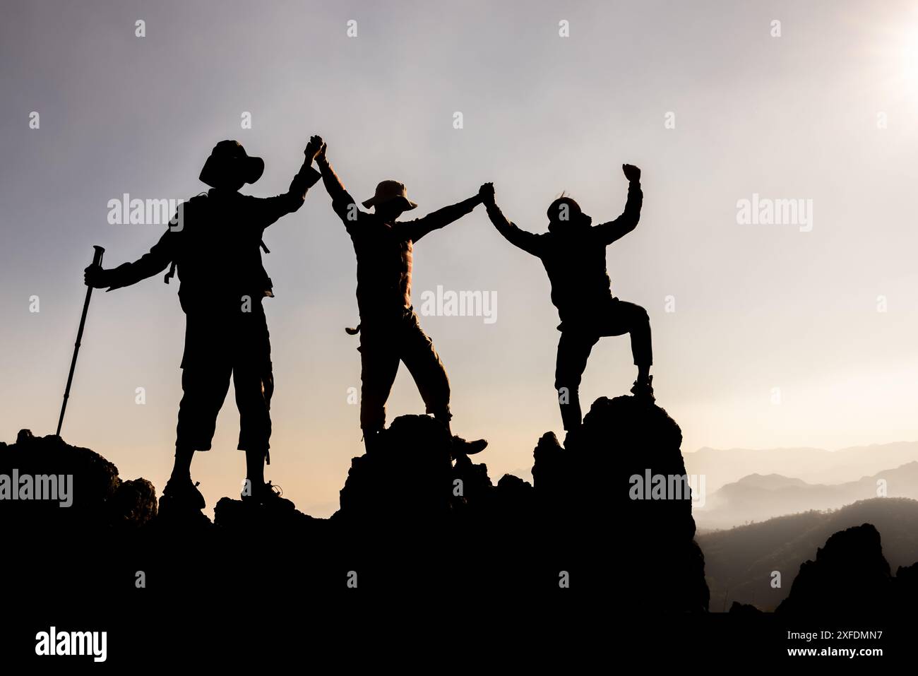 silhouette male and female hikers climbing up mountain cliff . helps ...
