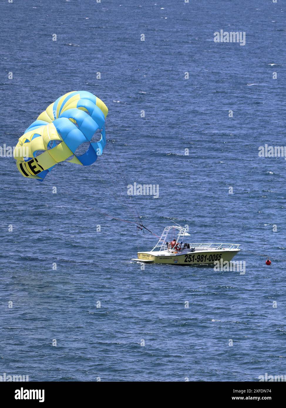 Boat pulling a parasail across sky over ocean Stock Photo - Alamy