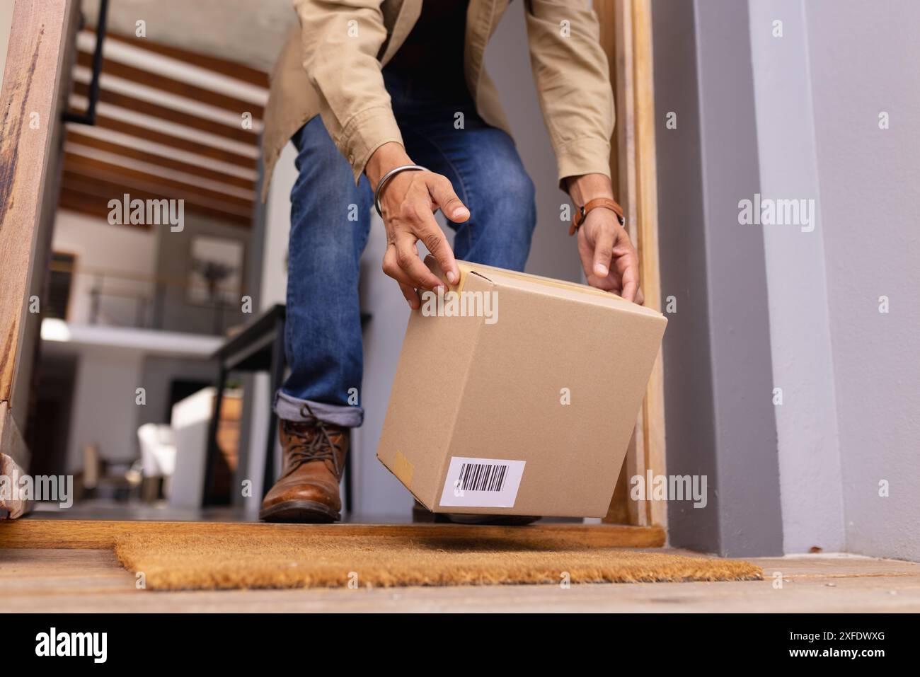 Receiving package delivery, man picking up cardboard box from doorstep ...