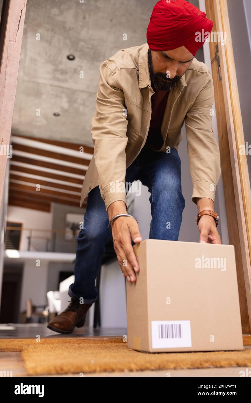 Delivering package, man in turban placing cardboard box at doorstep ...