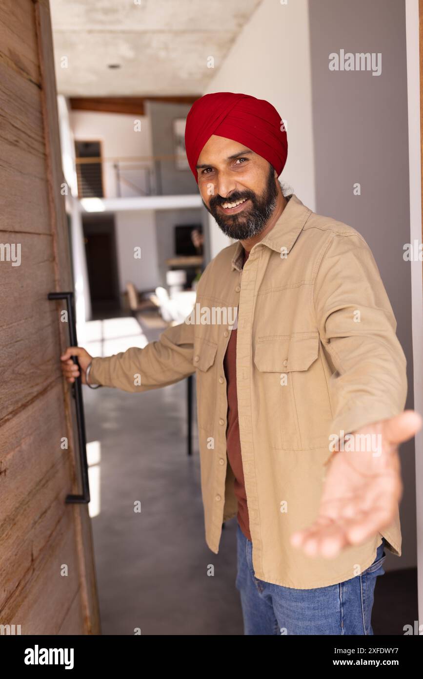 Welcoming guest, smiling Indian man in turban opening door at home ...