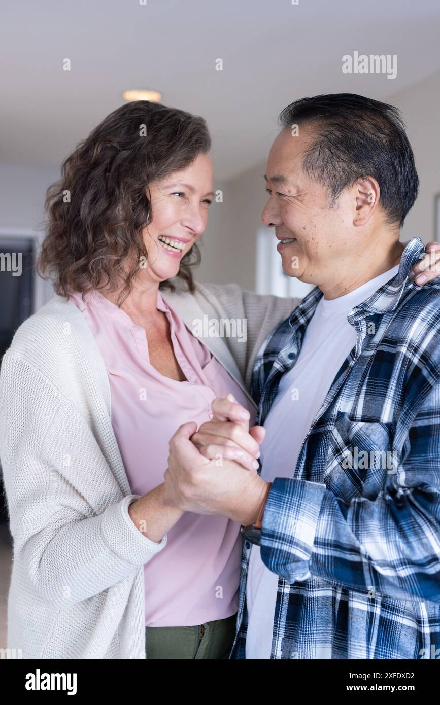 Dancing together, smiling senior couple enjoying their vacation indoors ...