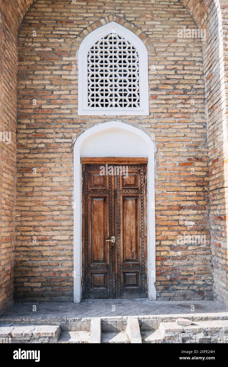 ancient carved wooden door with oriental Uzbek pattern in brick wall in ...