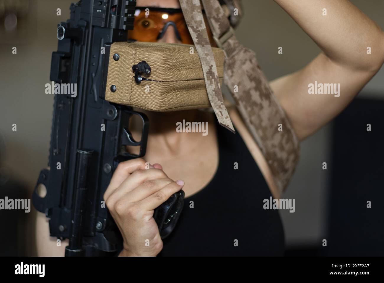 a young woman with an airsoft weapon in her hands and partially in ...