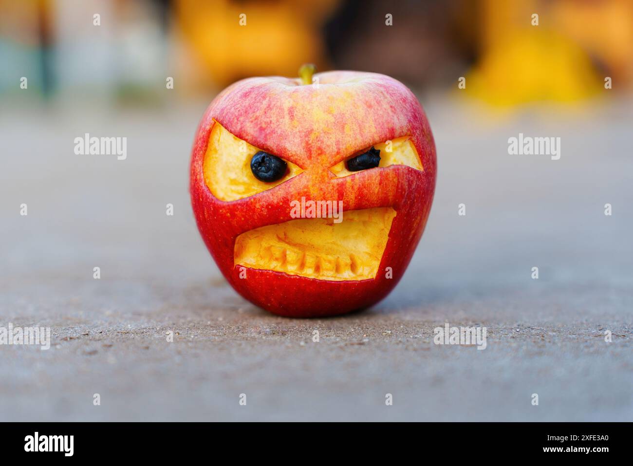 Creative apple with carved angry face, that has angry-looking eyes and ...