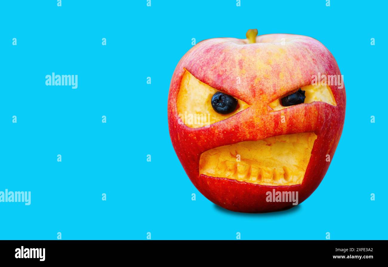 Red apple with carved angry-looking eyes and a frowning mouth isolated ...