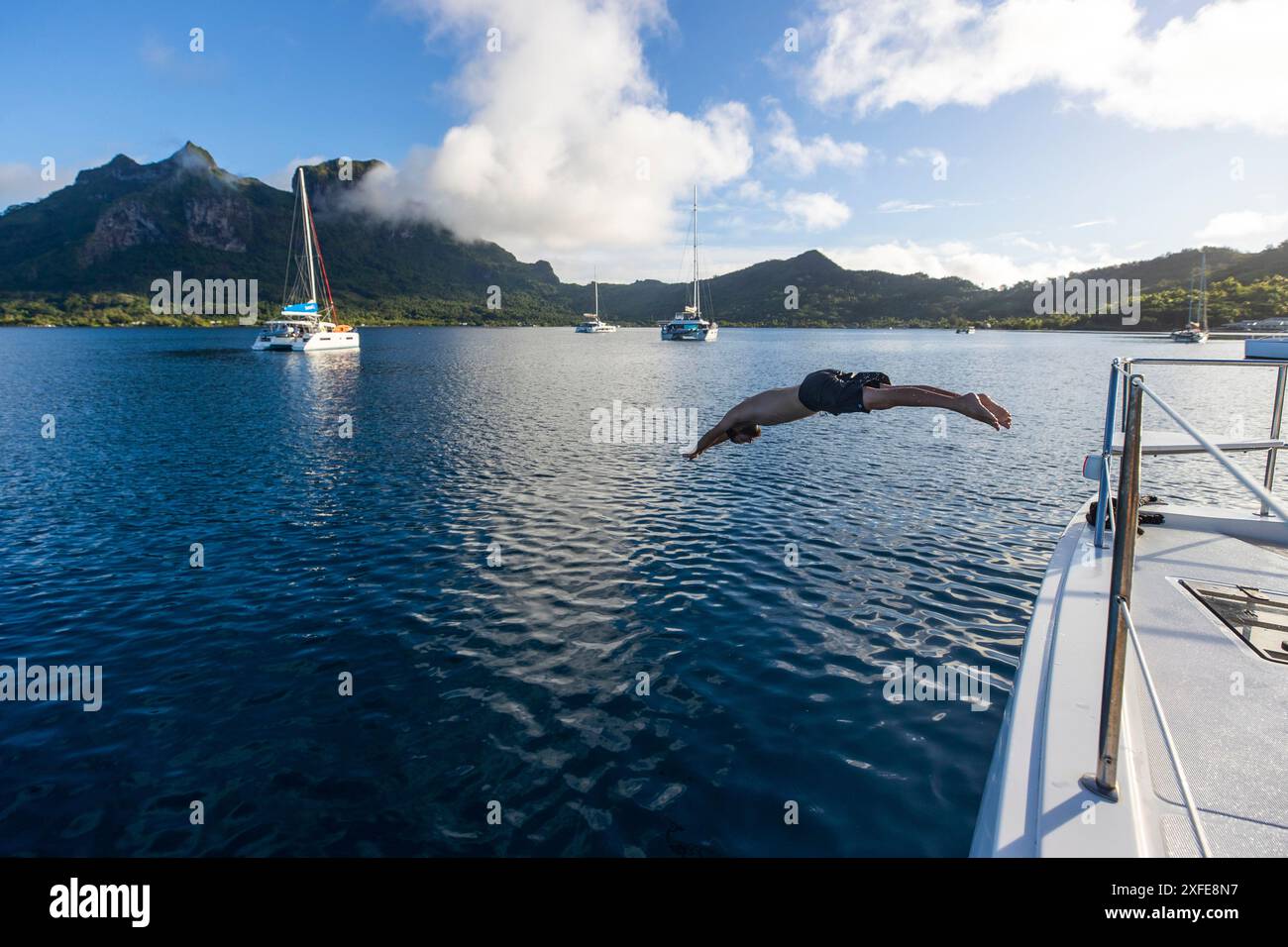 French Polynesia, Society Islands, man diving from a cruise sailboat at ...