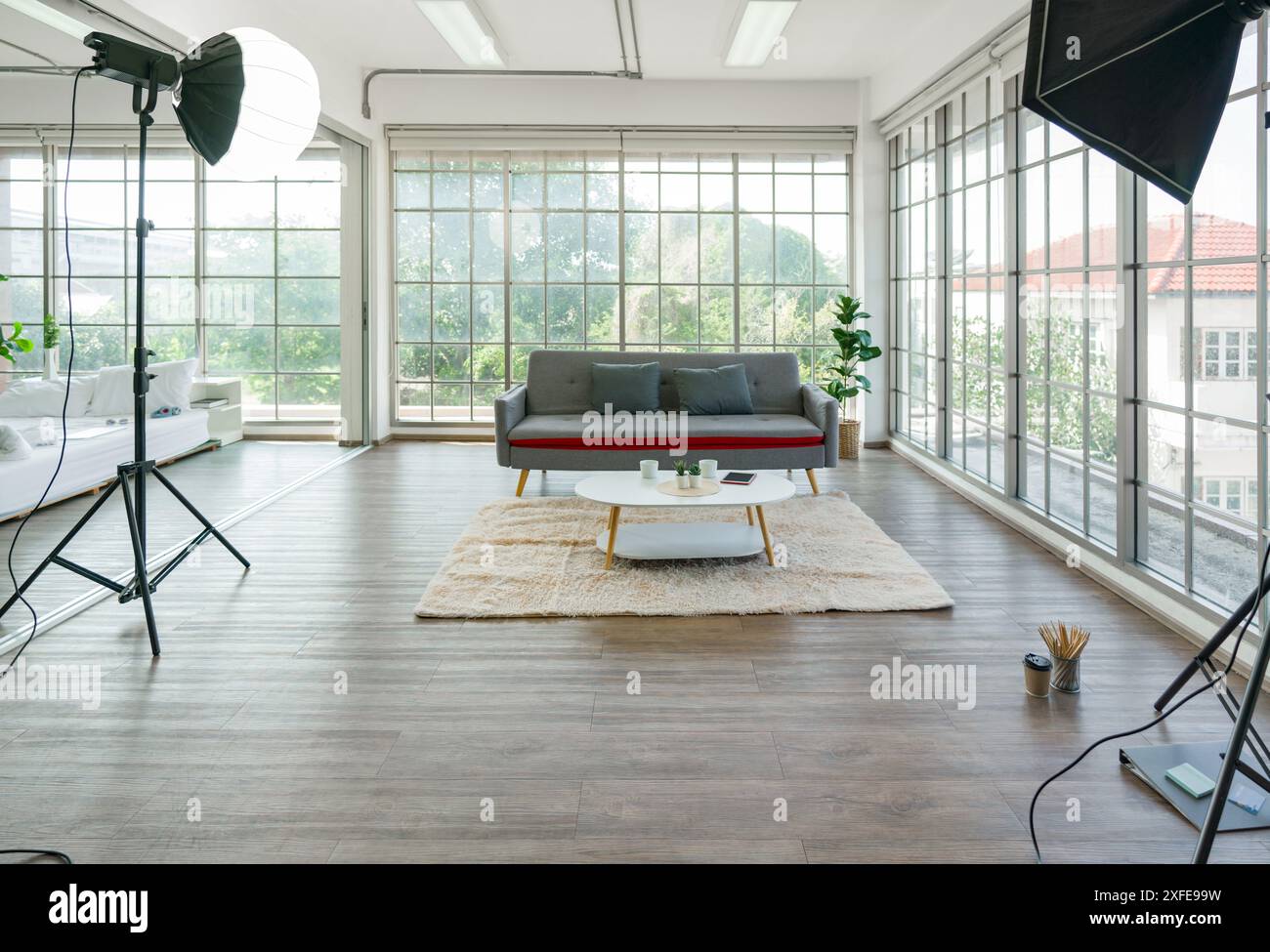 A bright, modern photo studio with large windows, cozy sofa, coffee ...