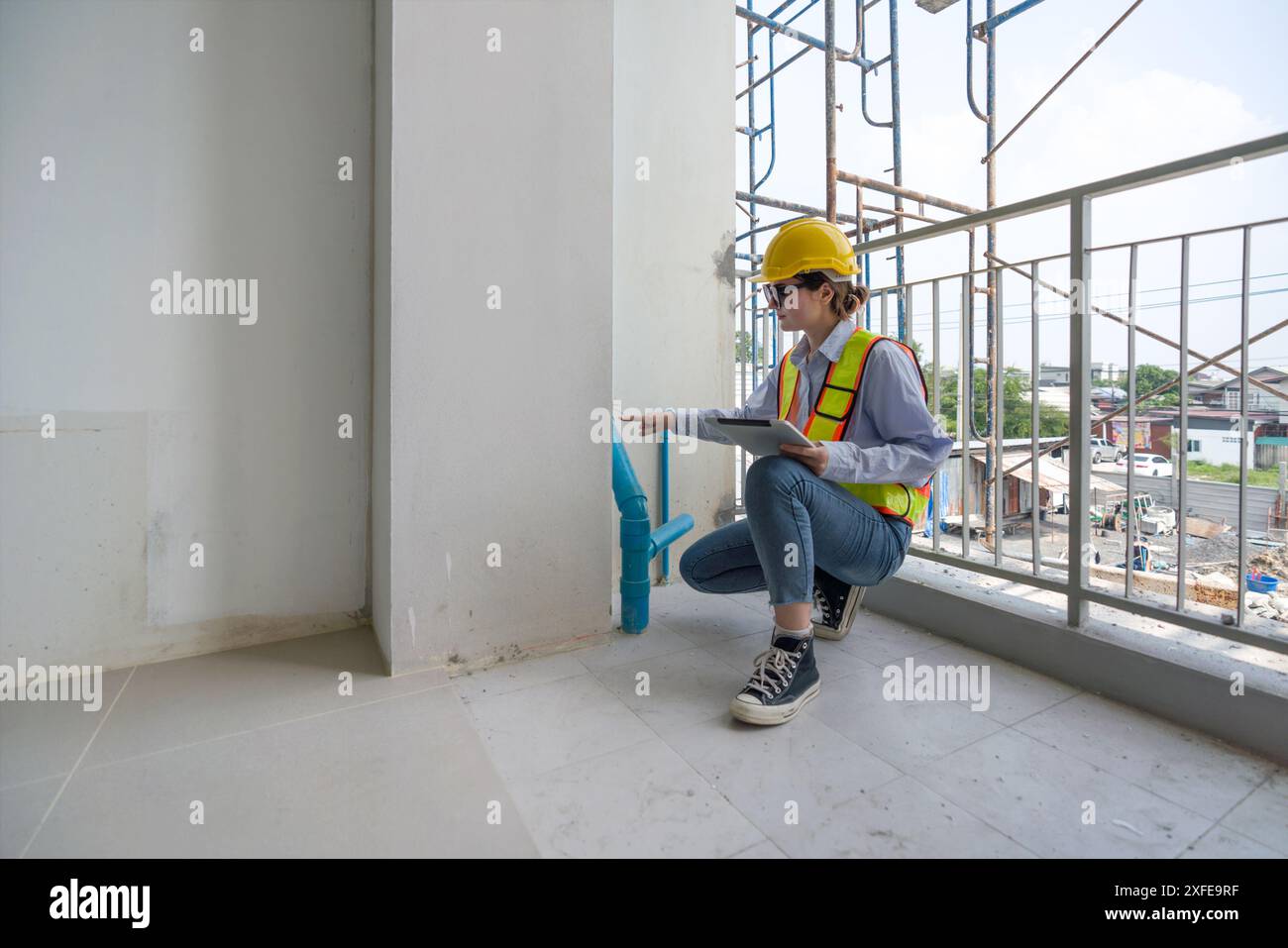 A construction worker is inspecting a building site. They are wearing ...