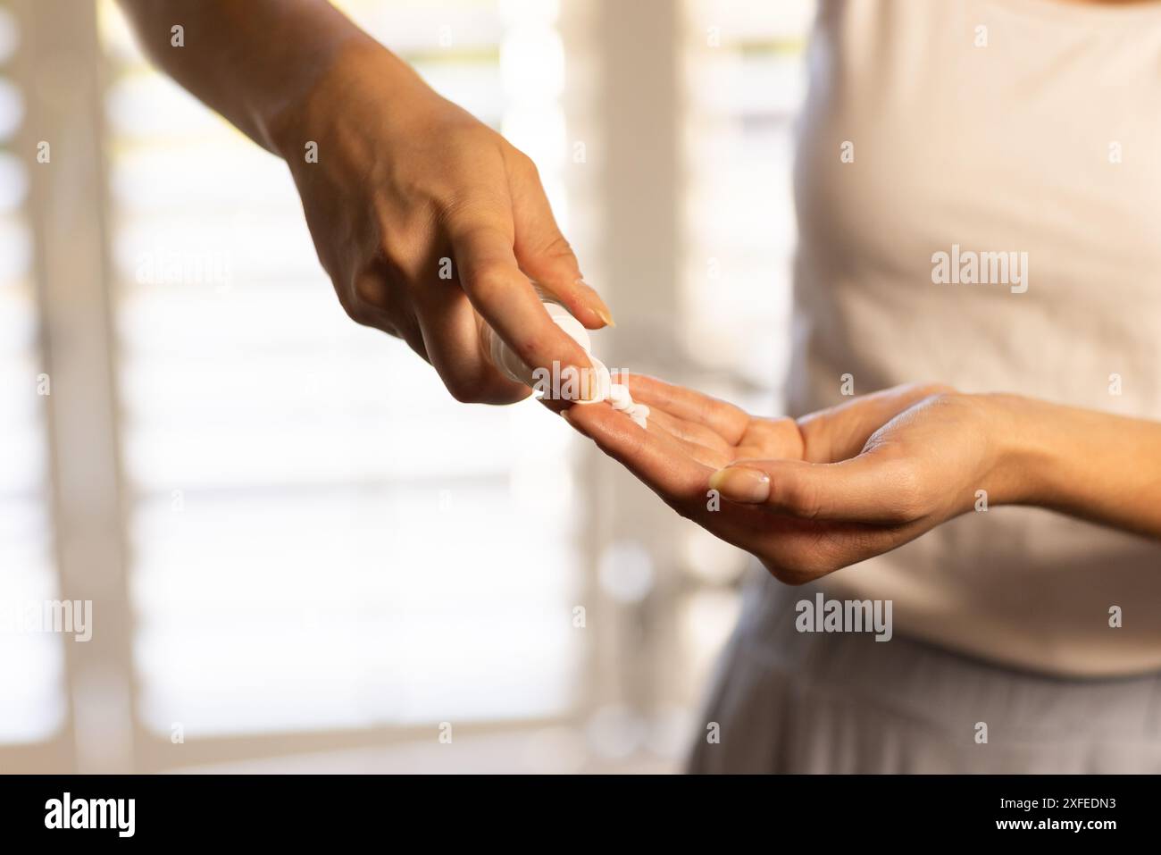 Applying lotion on hands, woman focusing on skincare routine at home ...