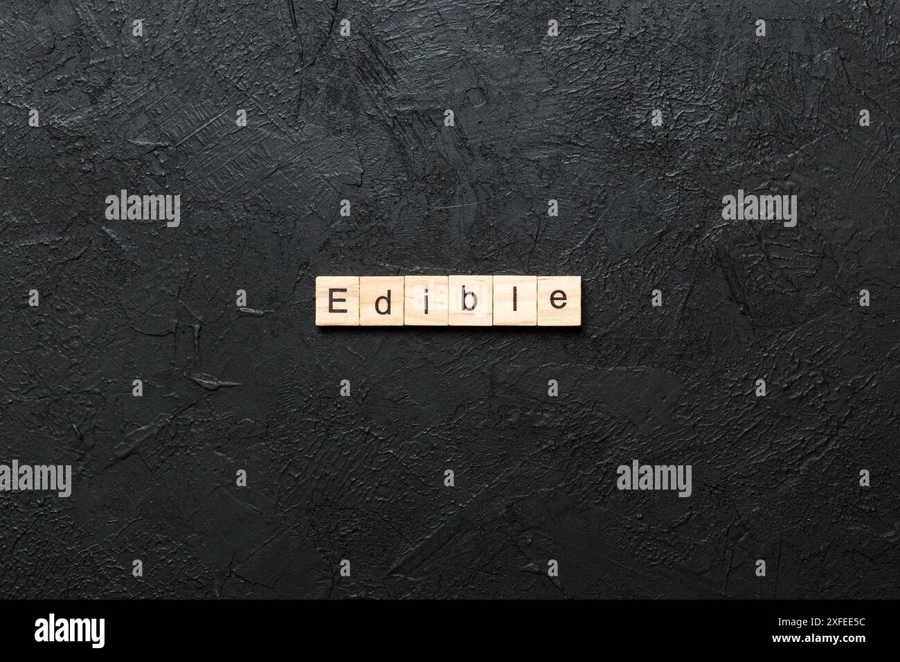 EDIBLE word written on wood block. EDIBLE text on cement table for your ...