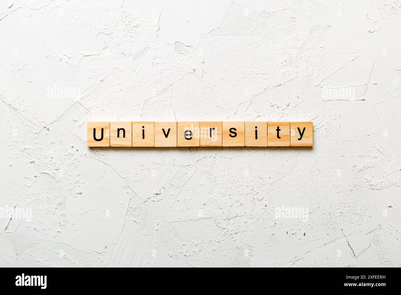 UNIVERSITY word written on wood block. UNIVERSITY text on cement table ...