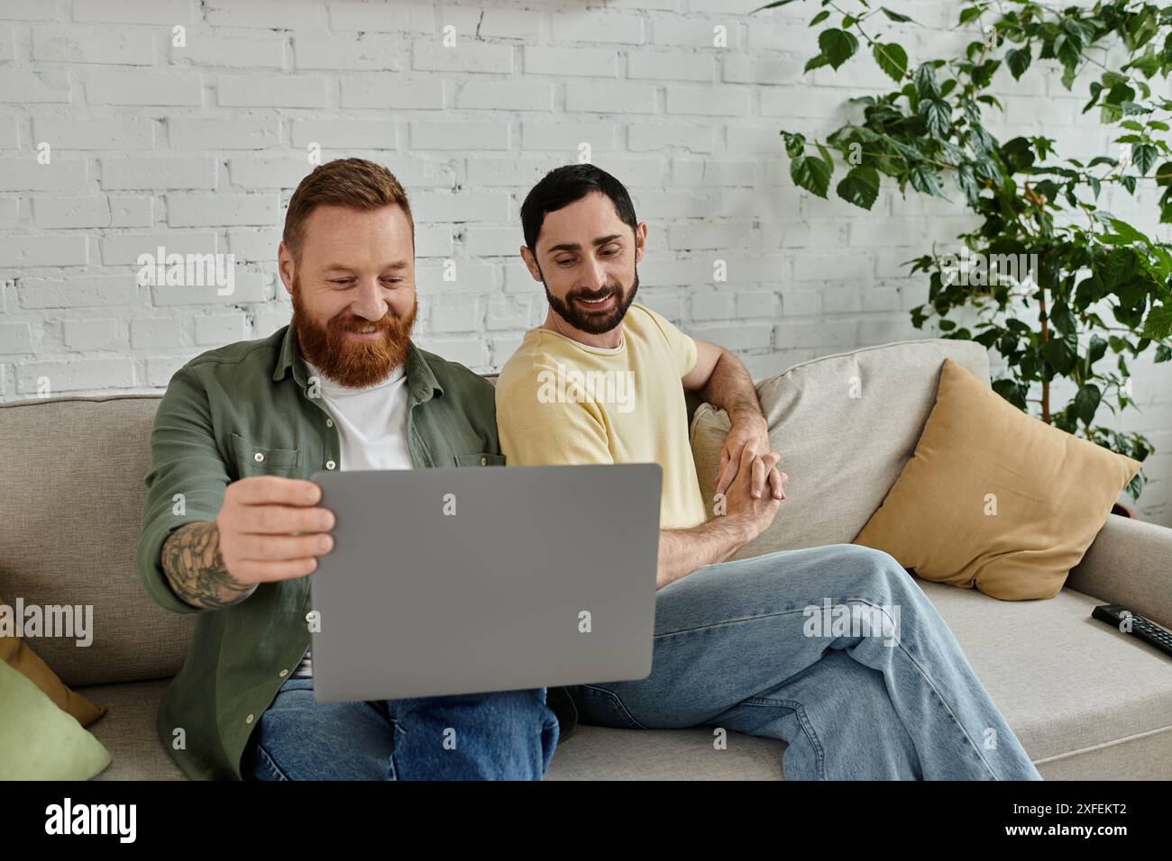 Bearded Gay Couple Seated On A Couch Focused On The Screen Of A Laptop In Their Cozy Living