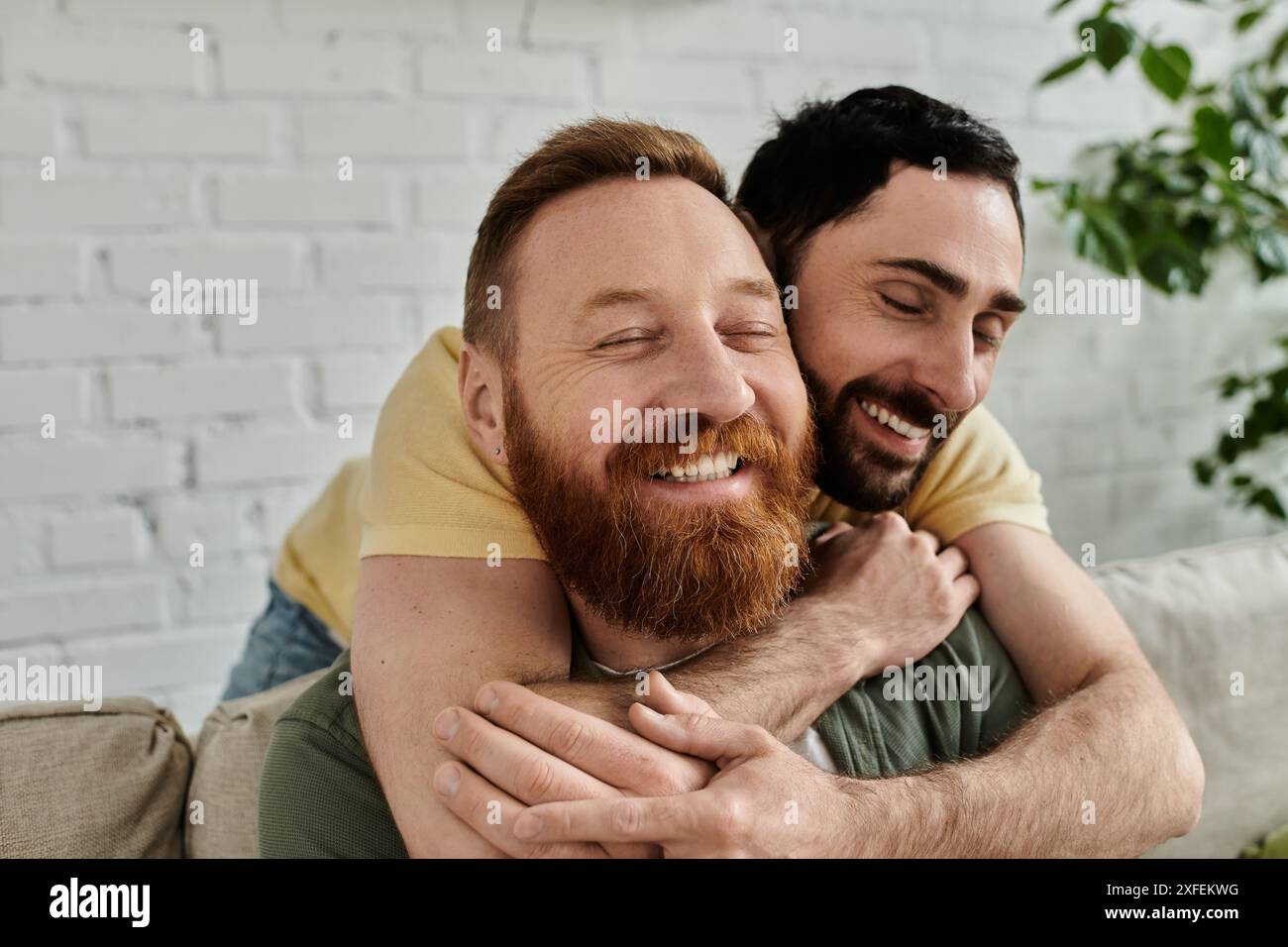 Bearded Gay Couple Hug Tenderly On A Comfortable Couch In Their Living Room Showing Love And