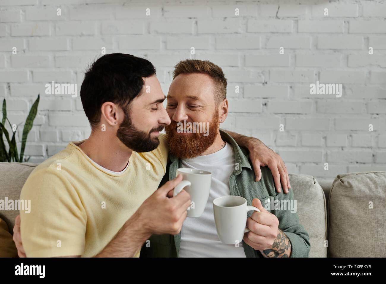 A duo of bearded men sitting closely together on a comfortable couch in ...