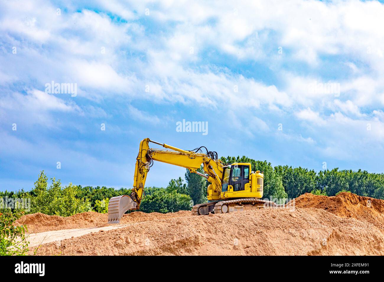 digger at a sandy heap with big shovel under blue and cloudy sky Stock ...