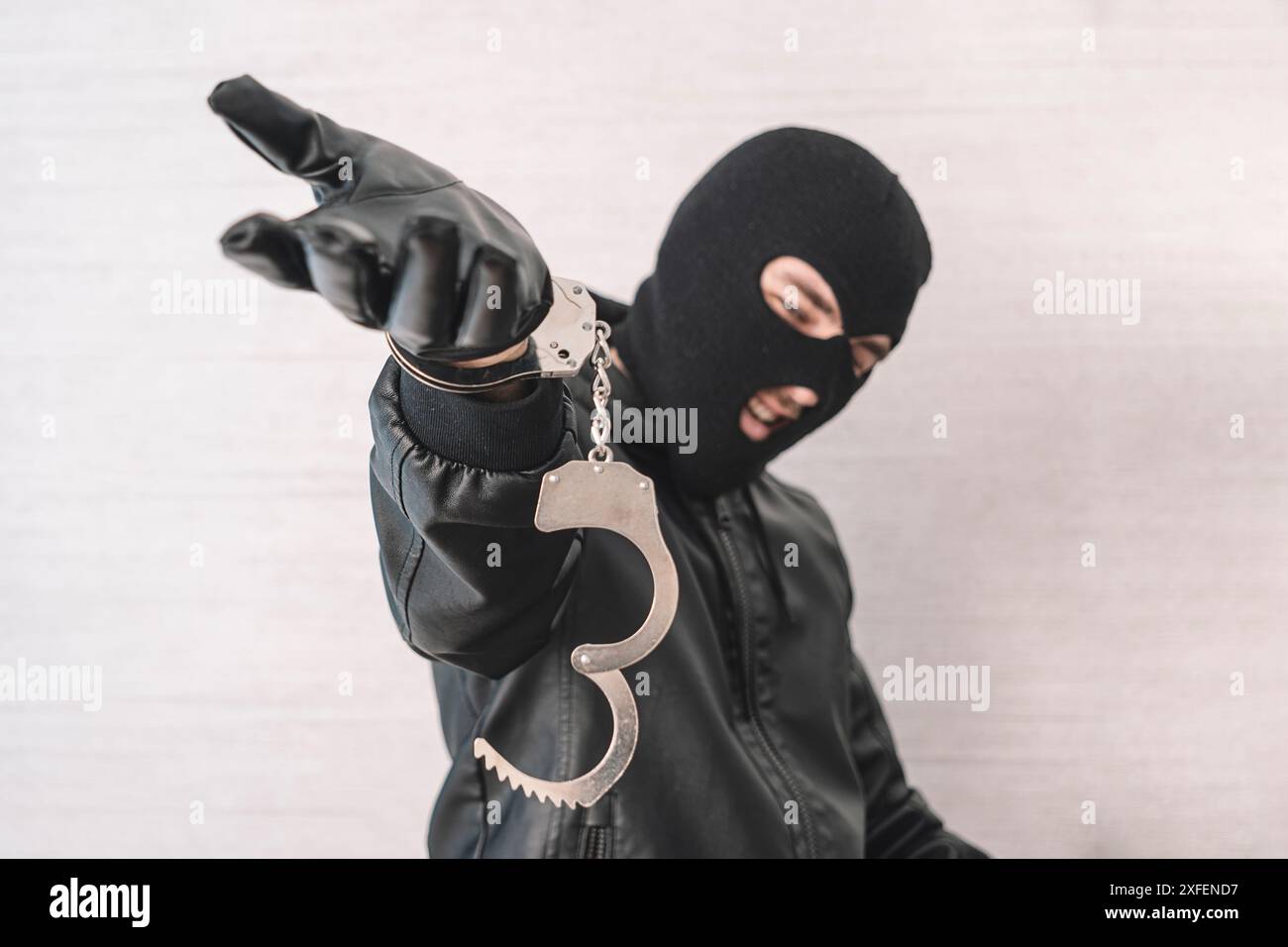 a bandit in a black mask and gloves with handcuffs in his hands on a ...