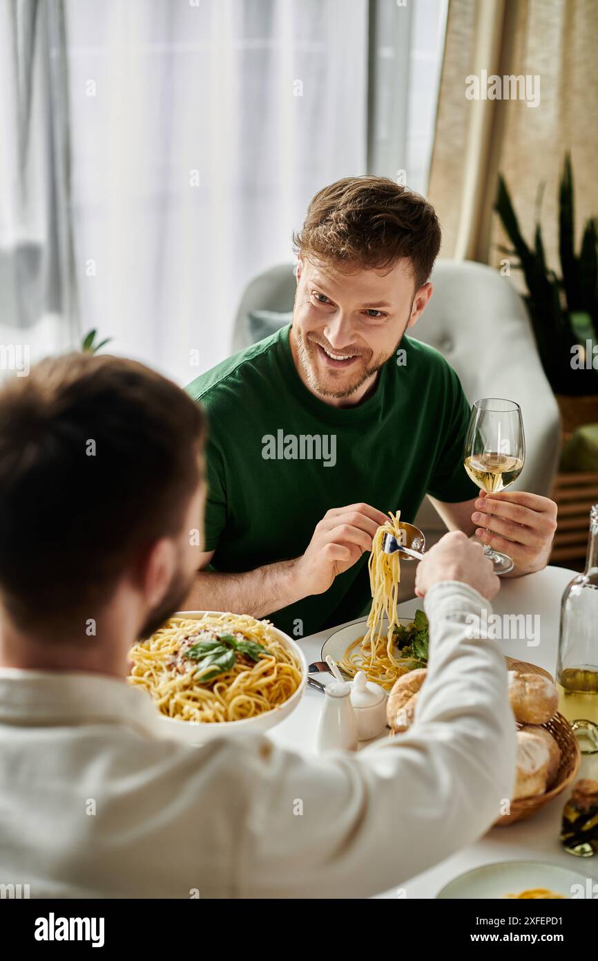 A gay couple enjoys a meal together at home, sharing a moment of ...
