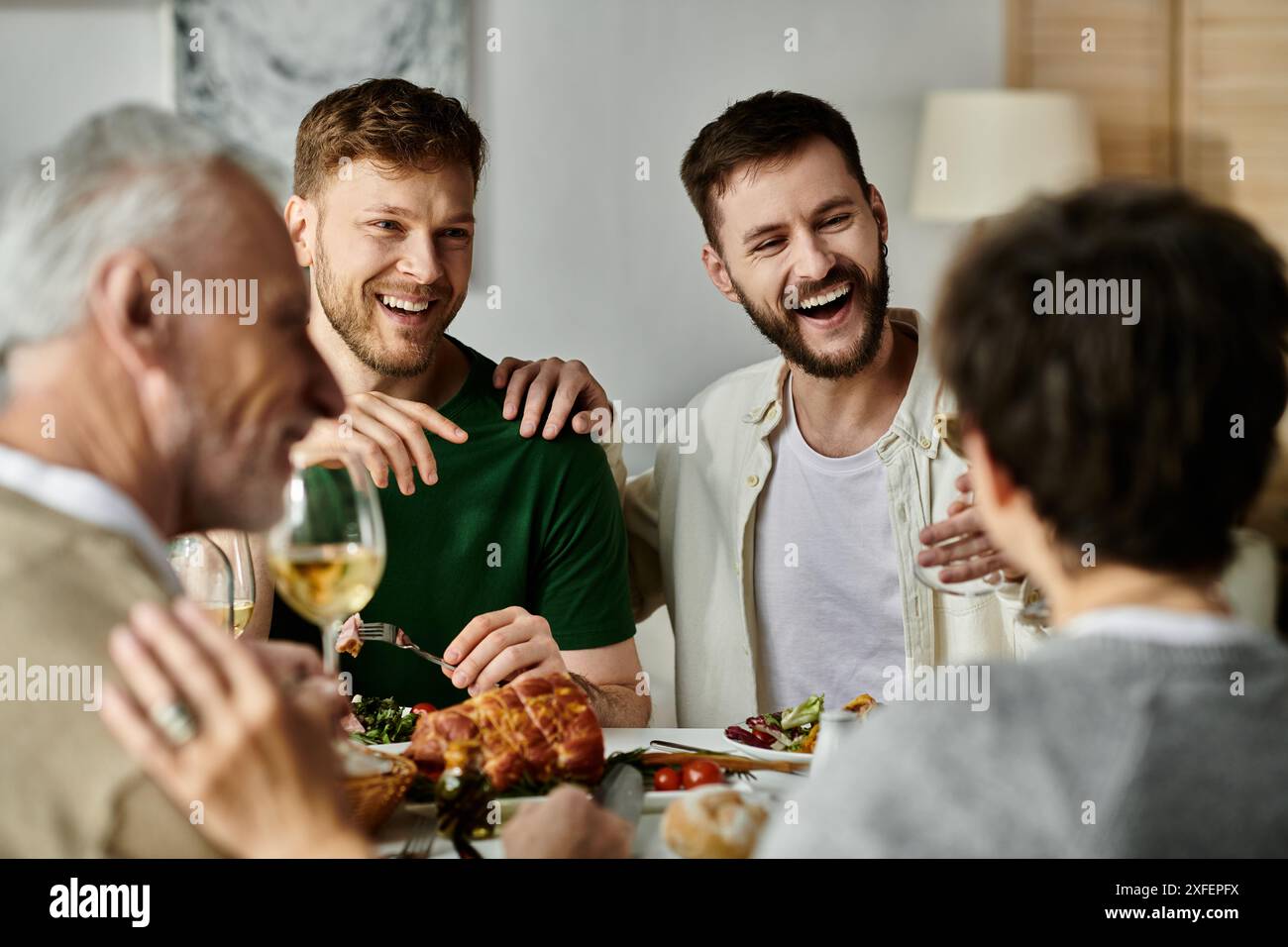 A gay couple enjoys a meal with their family, sharing laughs and conversation Stock Photo - Alamy