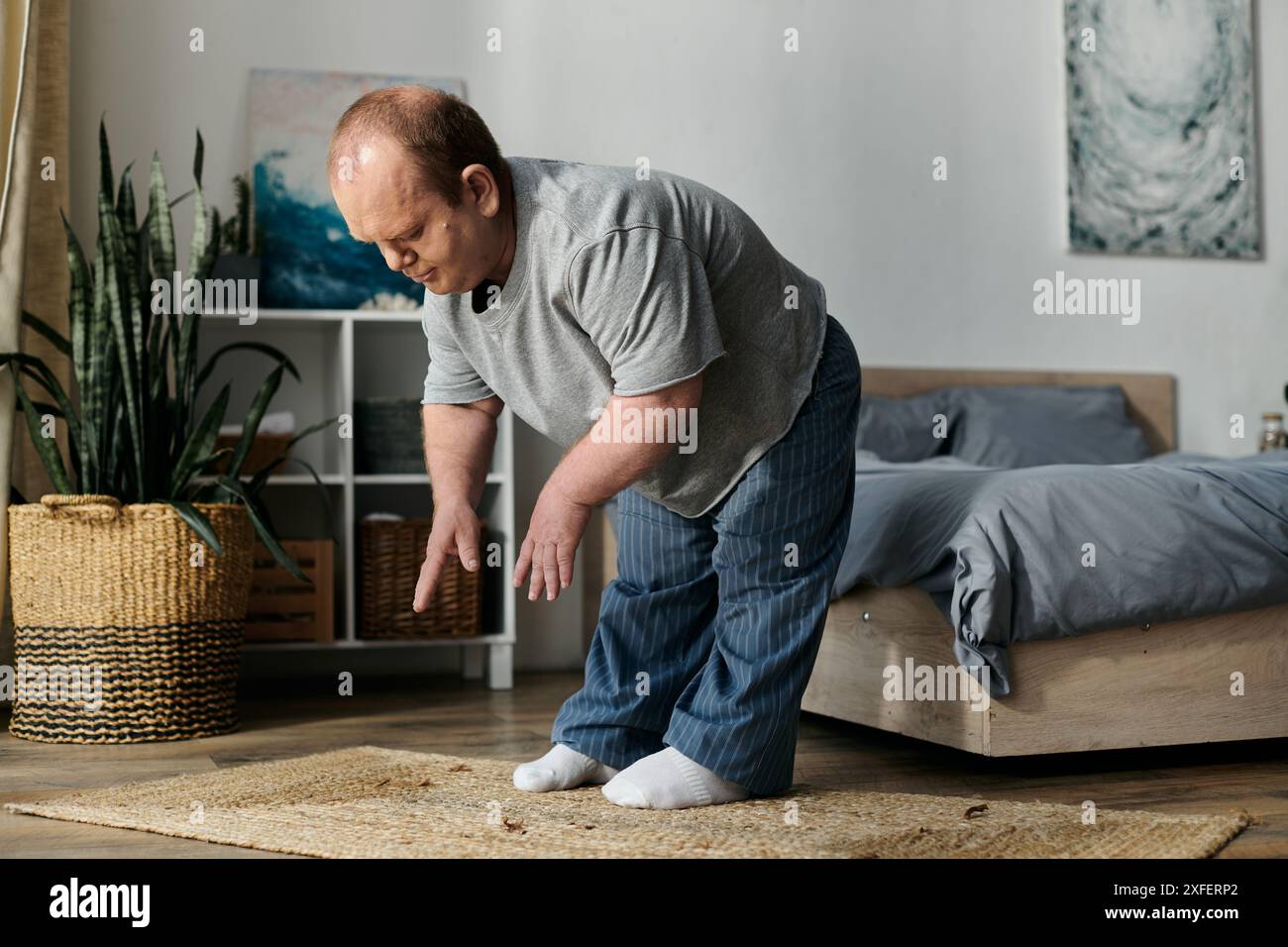 A man with inclusivity in pajamas stretches on a rug in a bedroom Stock ...