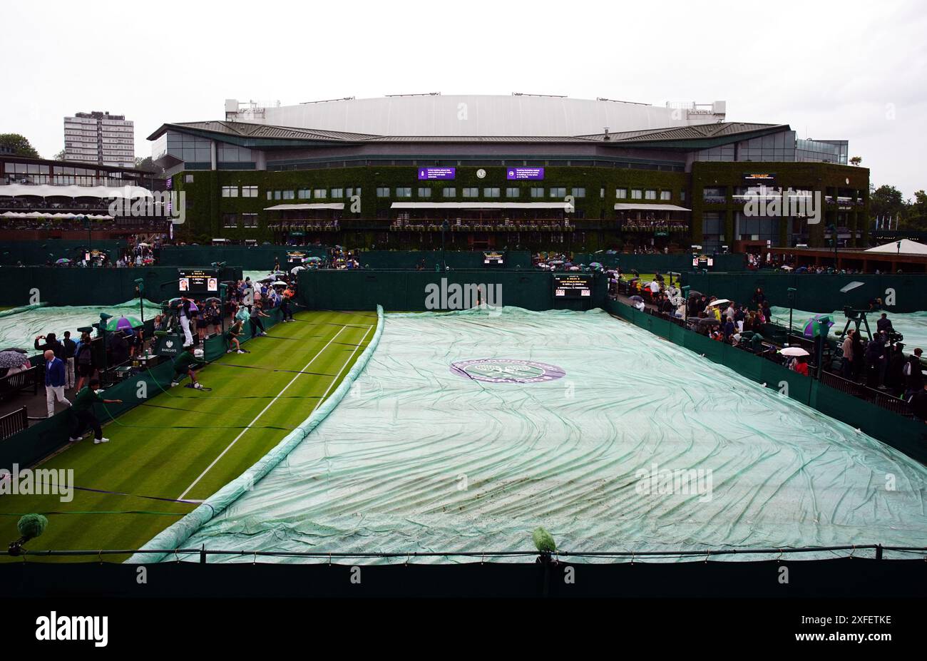 Ground staff pull covers onto court 10 as rain stops play on day three ...
