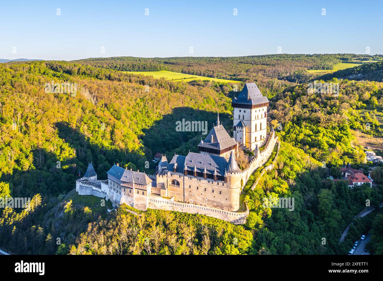 Aerial perspective of Karlstejn Castle nestled in a forested landscape ...