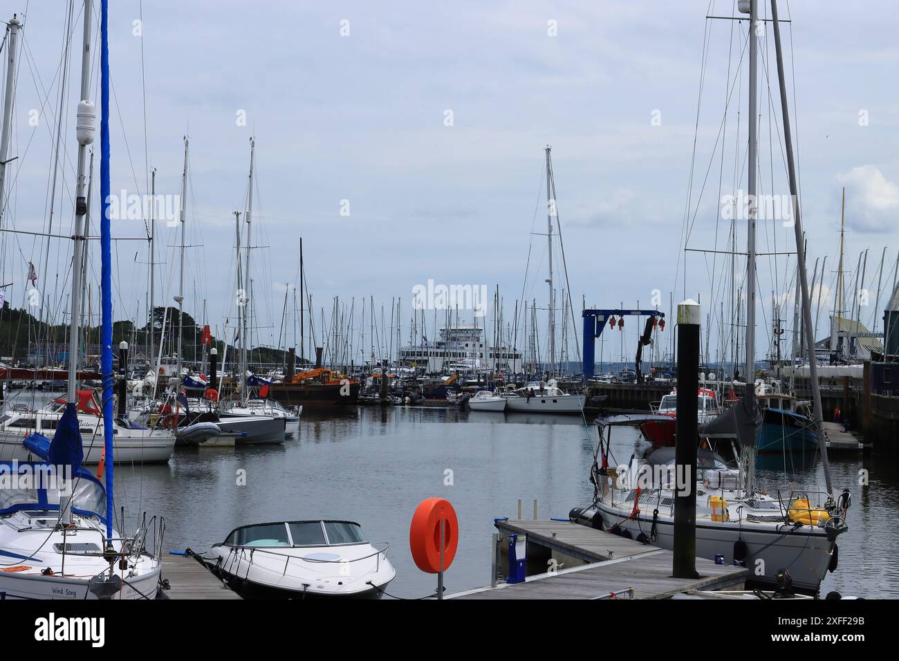 Lymington Harbour, England. 18 June 2024. Sailing boats and motor boats with the Wightlink ferry ...