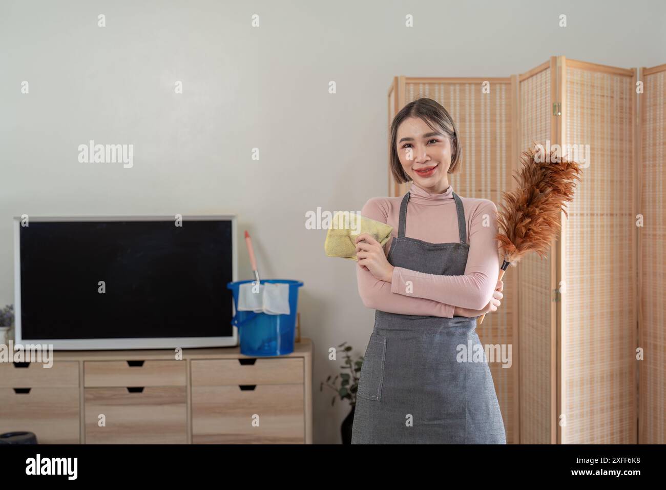 Housekeeper Smiling While Holding Cleaning Tools in a Modern Living ...