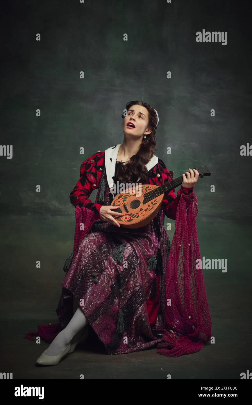 Portrait of beautiful young woman playing with a lute against vintage ...