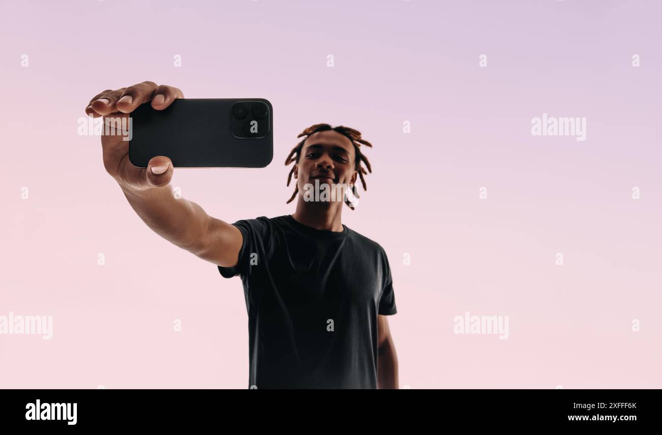 Gen Z man with dreadlocks uses a smartphone to take a selfie. The ...