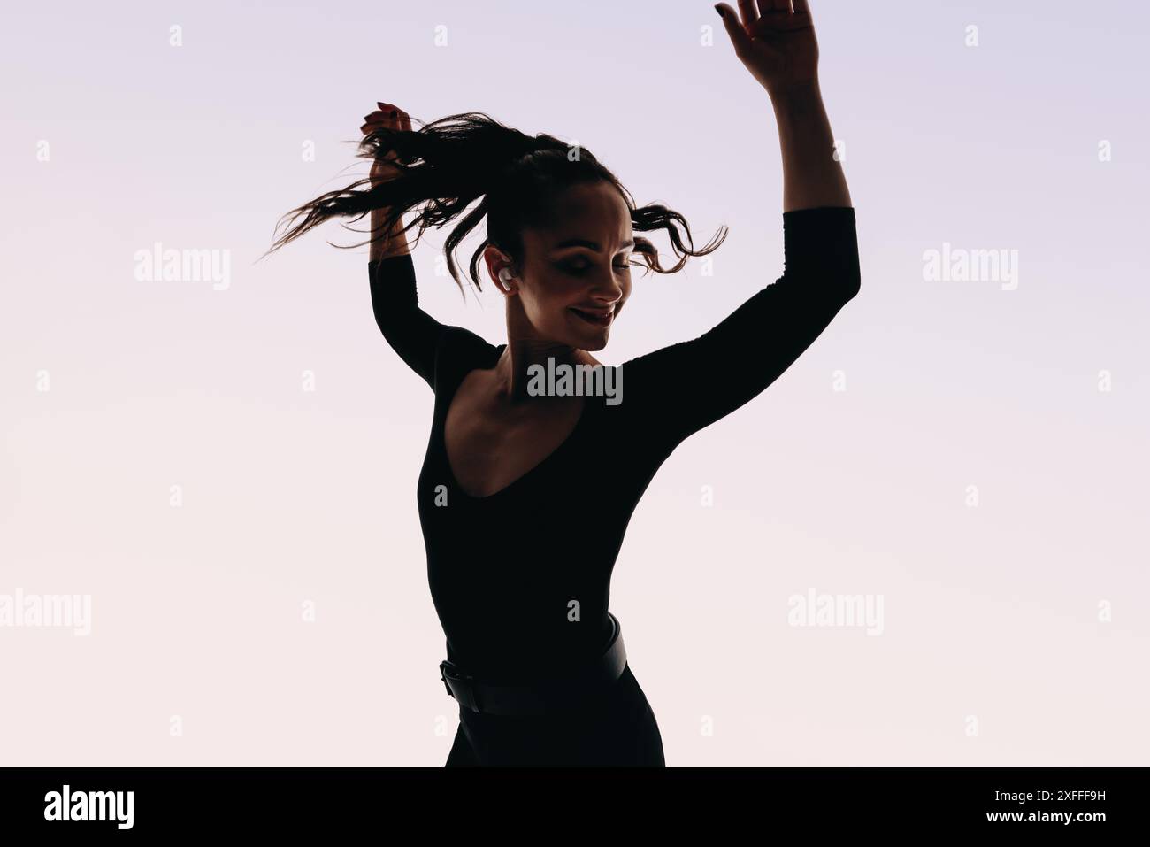 Happy woman with a toned physique dances expressively. Her silhouetted ...