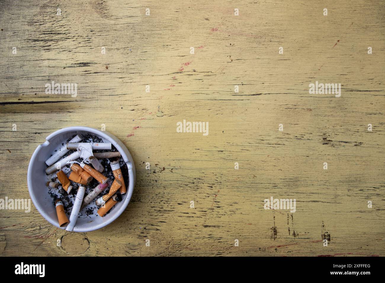 Cigarette butt-filled ashtray on cafe patio table Stock Photo - Alamy