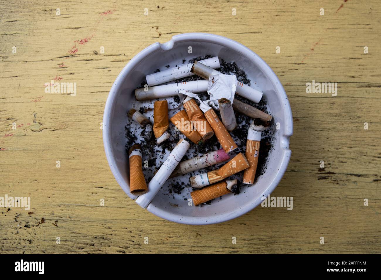 Cigarette butt-filled ashtray on cafe patio table Stock Photo - Alamy