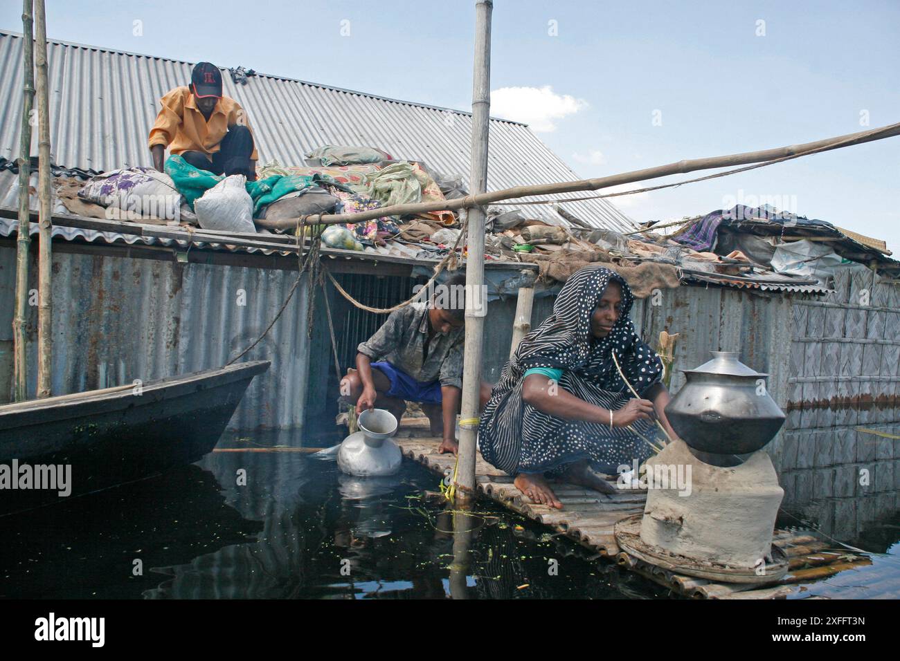 A woman cooking on a bamboo platform made with her flooded house at ...