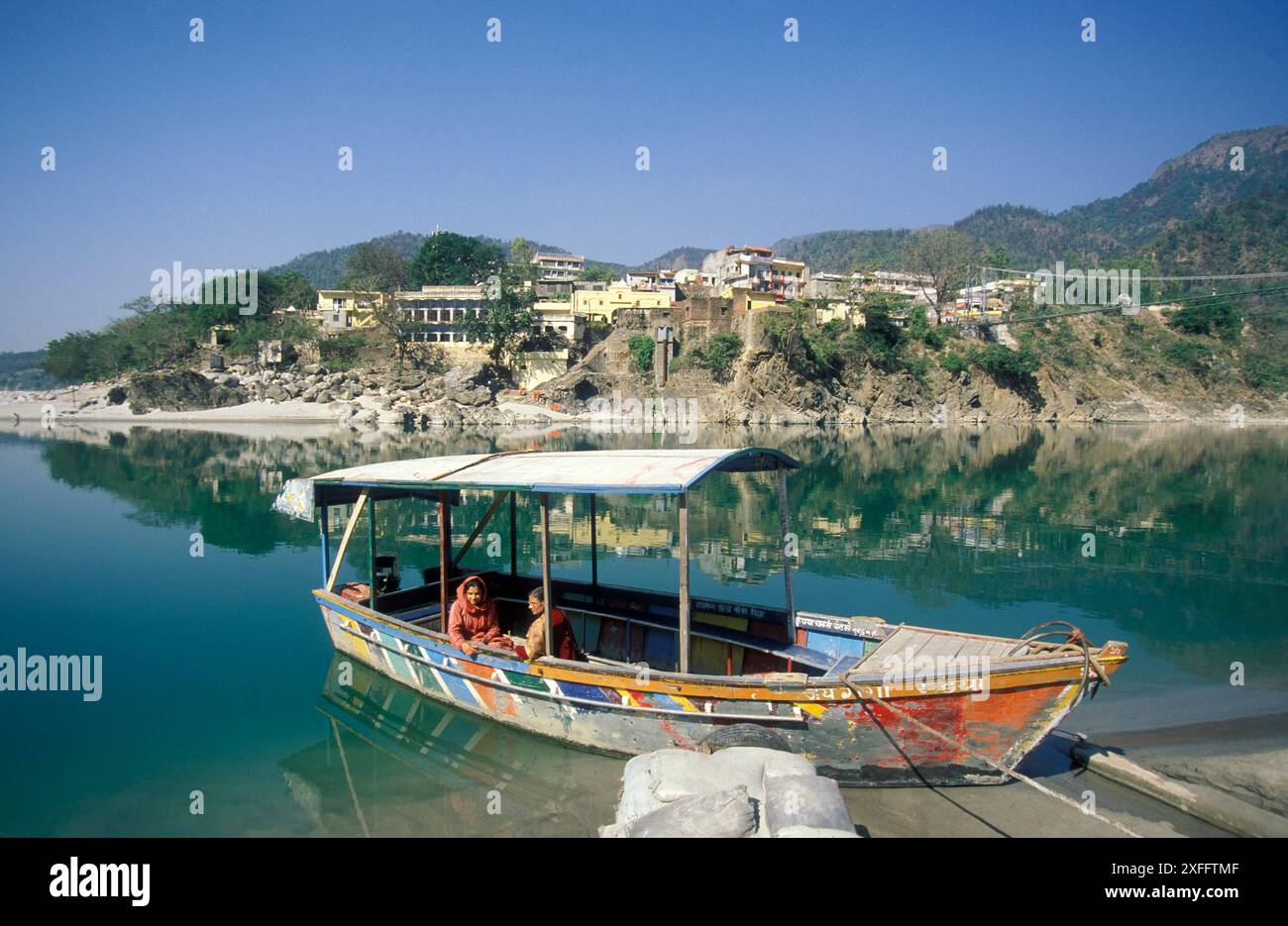 a Boat on the Holy Ganges River with the city of Rishikesh in the ...