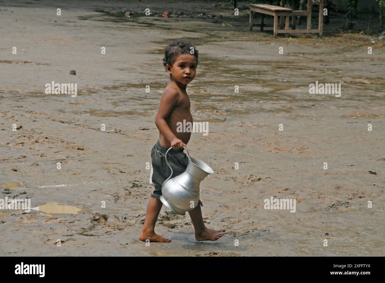 A boy walks with a jug to collect drinking water at a shelter in Basabo ...